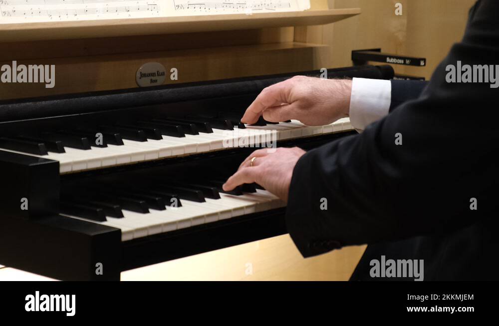 Hands close up of a pipe organist playing on the pedal board of a pipe ...