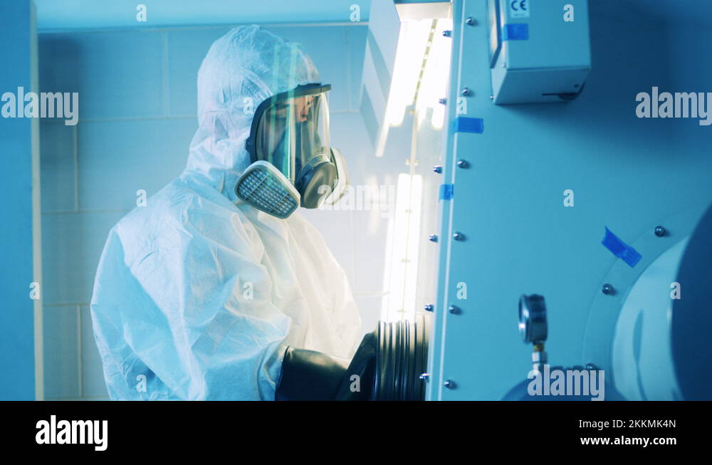 Laboratory worker in a hazmat suit is operating a vacuum cabinet Stock ...