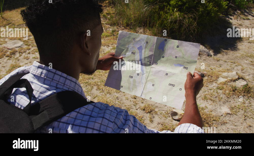 African american man hiking reading a map in coastal countryside Stock ...
