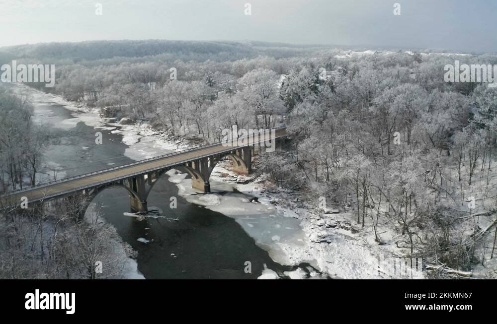 Arch bridge over frozen river in foresty area. Aerial drone turn view ...