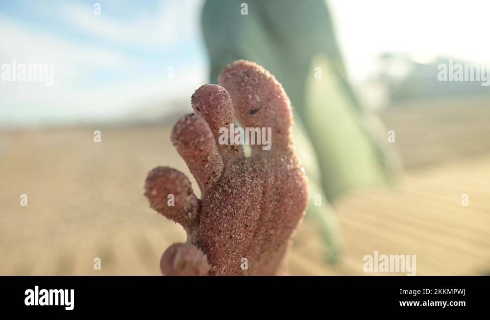 Close-up of foot and toes in the sand of a young girl in slow motion ...