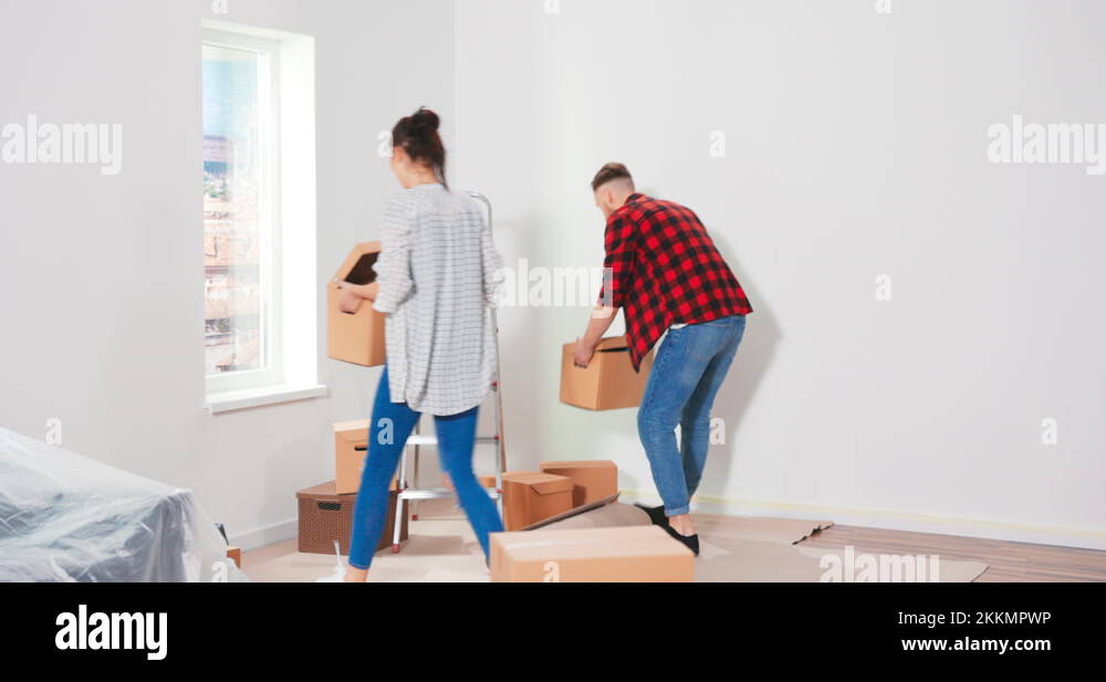 Happy married 20s couple move into new first house bring carton boxes ...
