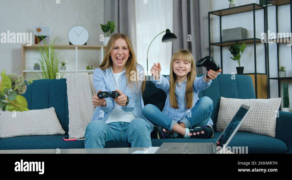 Lovely friendly cheerful two different ages girls playing video games ...