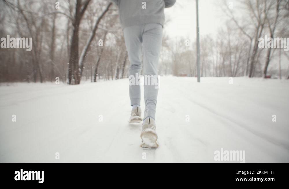 Running athlete in winter park, rear view, closeup. Back view of a ...