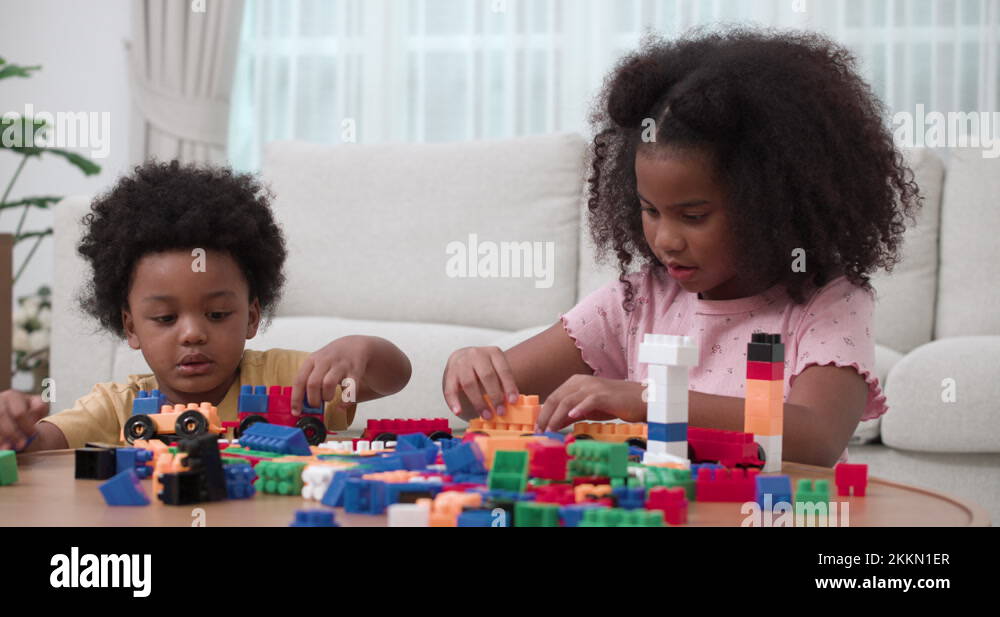 An older African sister help her little brother making a train with a ...