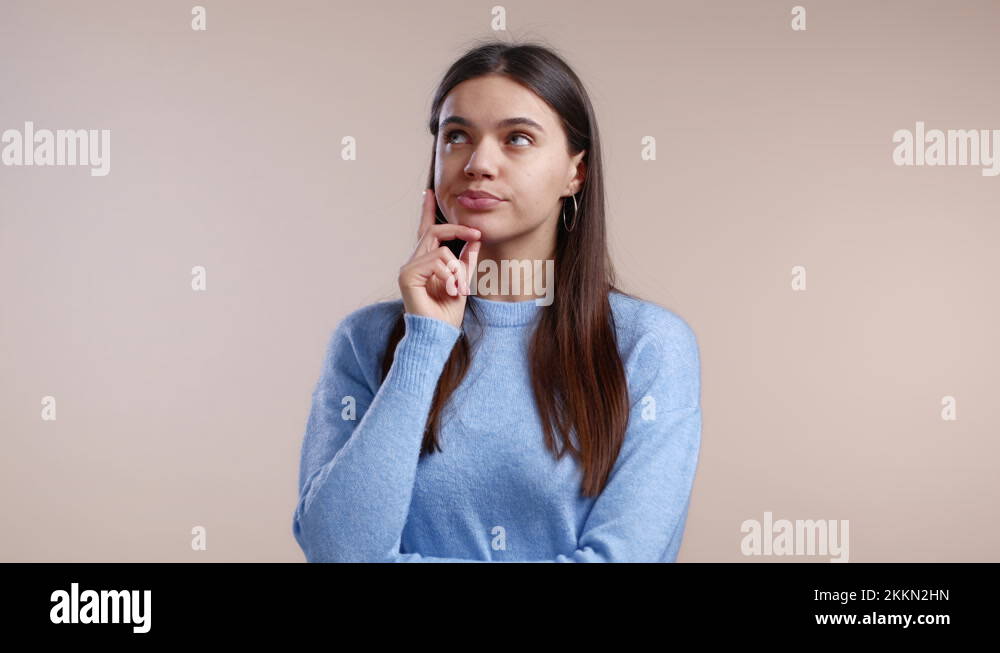 Thinking woman looking up and around on studio background. Pensive face ...
