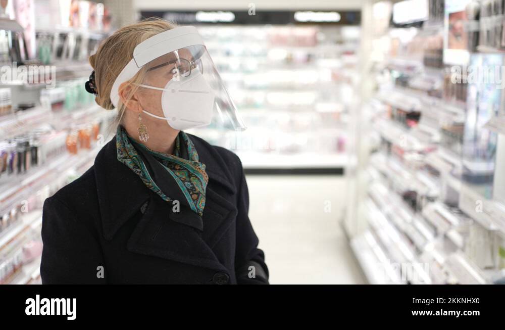 Woman wearing ppe face shield and mask shopping in the makeup cosmetics ...