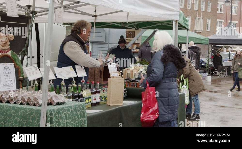 Stall holder takes payment from a customer on mobile phone in Farmers ...