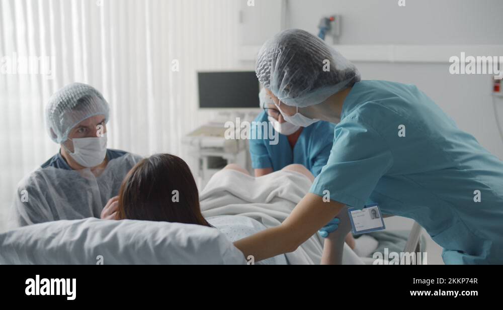 Woman giving birth with husband holds her hand in support and ...