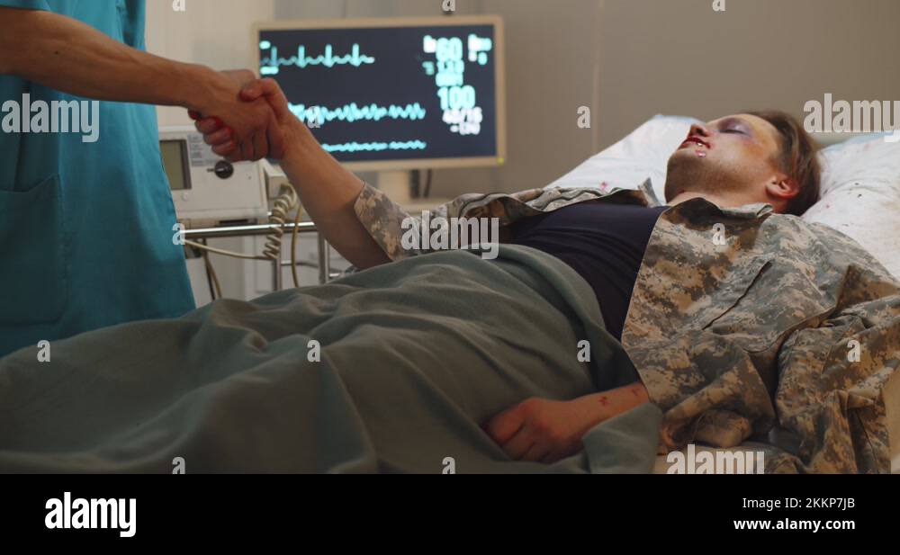 Injured soldier lying in hospital and shaking hands with doctor Stock ...