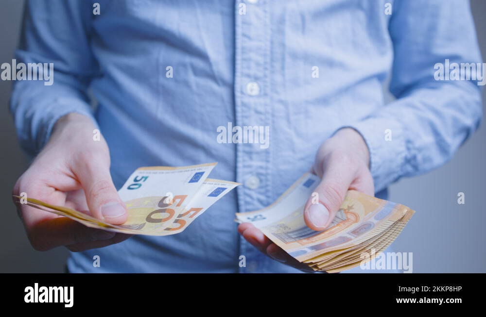 Sharp dressed man counting paper money bills and giving them to someone ...