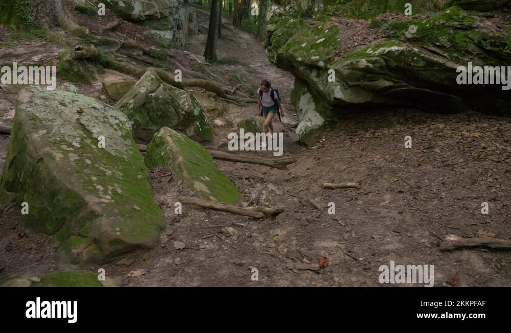A young female backpacking hiker climbing through an enchanting ravine ...