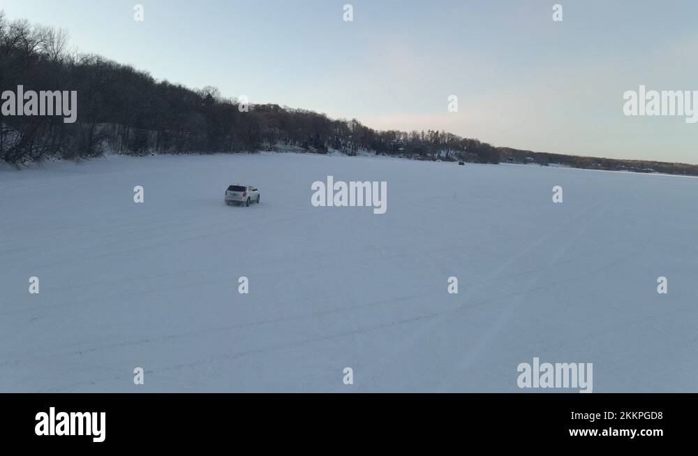 Aerial footage of an SUV driving on a Frozen lake, winter road trip ...