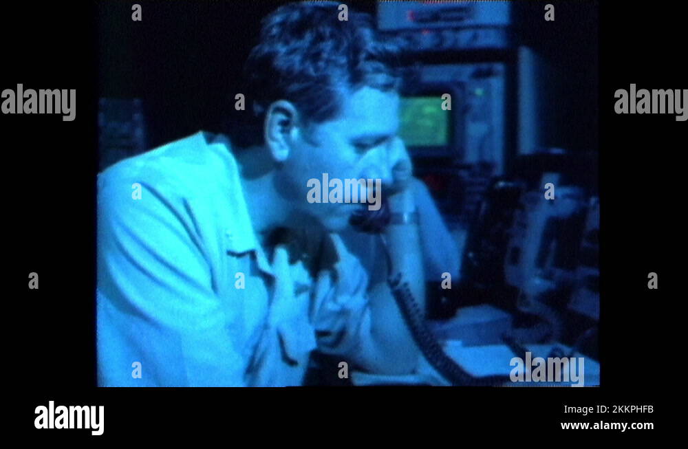 1980s: Man talks into telephone receiver on Navy ship. Submarine under ...