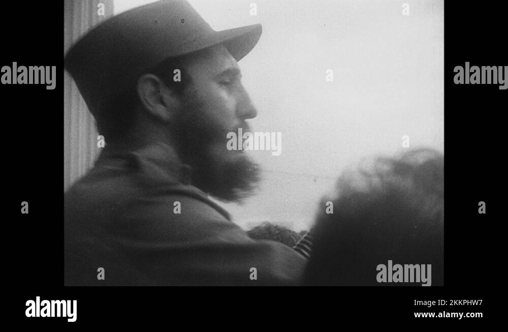 1960s Cuba: Crowd of people holds signs, cheers. Fidel Castro speaks to ...