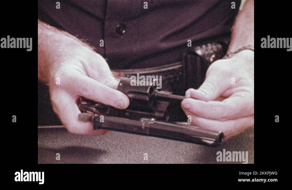 1970s: The cylinder of a revolver. Cop's hands open and close the ...