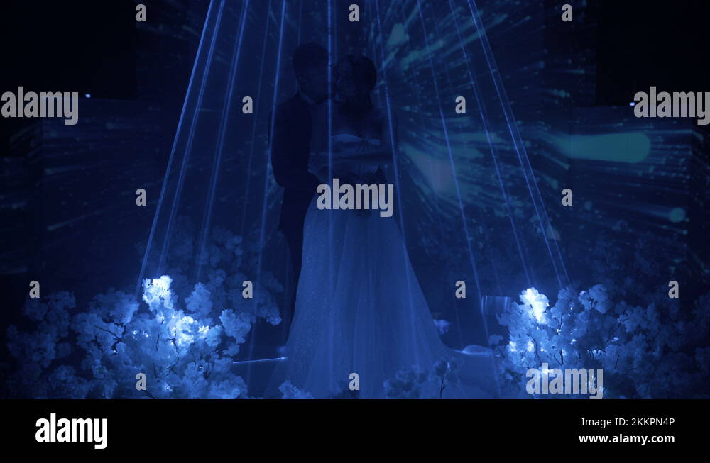 A young couple stands in a circle of laser projection, on their ...
