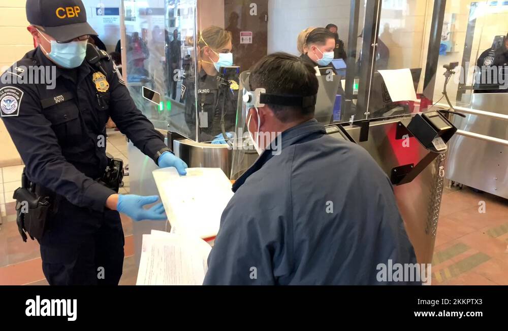 Mexican immigrant passing documents to CBP official at processing ...