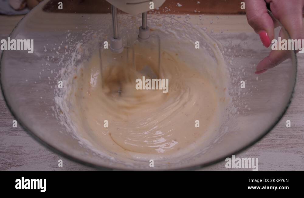 pouring condensed milk into cream being whipped with mixer slow motion ...