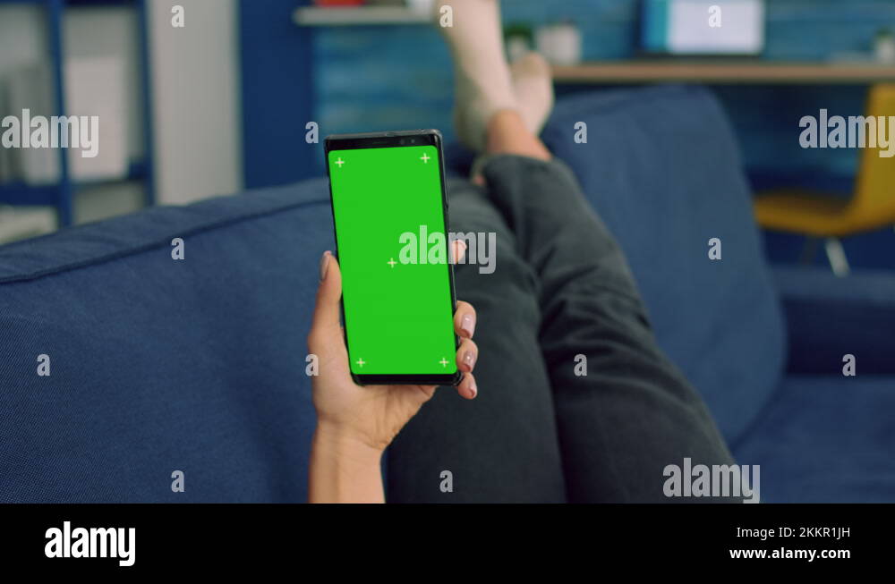 Freelancer woman lying on sofa looking at mock up green screen chroma ...