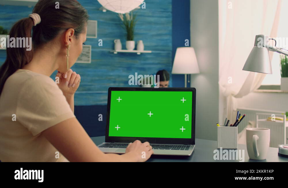 Freelancer looking at laptop computer with mock up green screen chroma ...