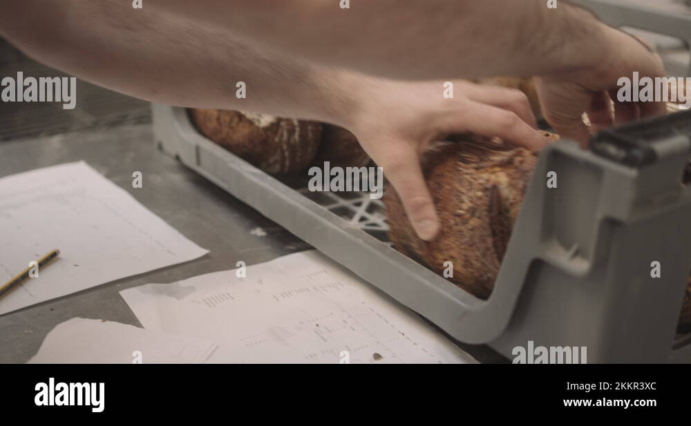 Busy Bearded male baker wearing apron in bakery packing bread for ...