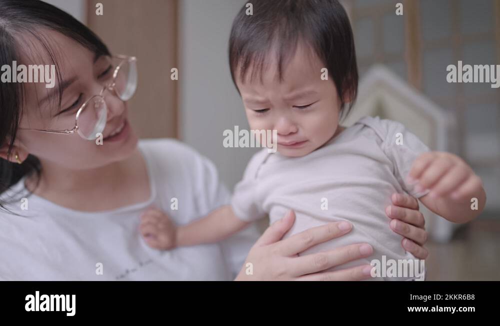 Adorable baby girl crying next to her mother, childhood emotional ...