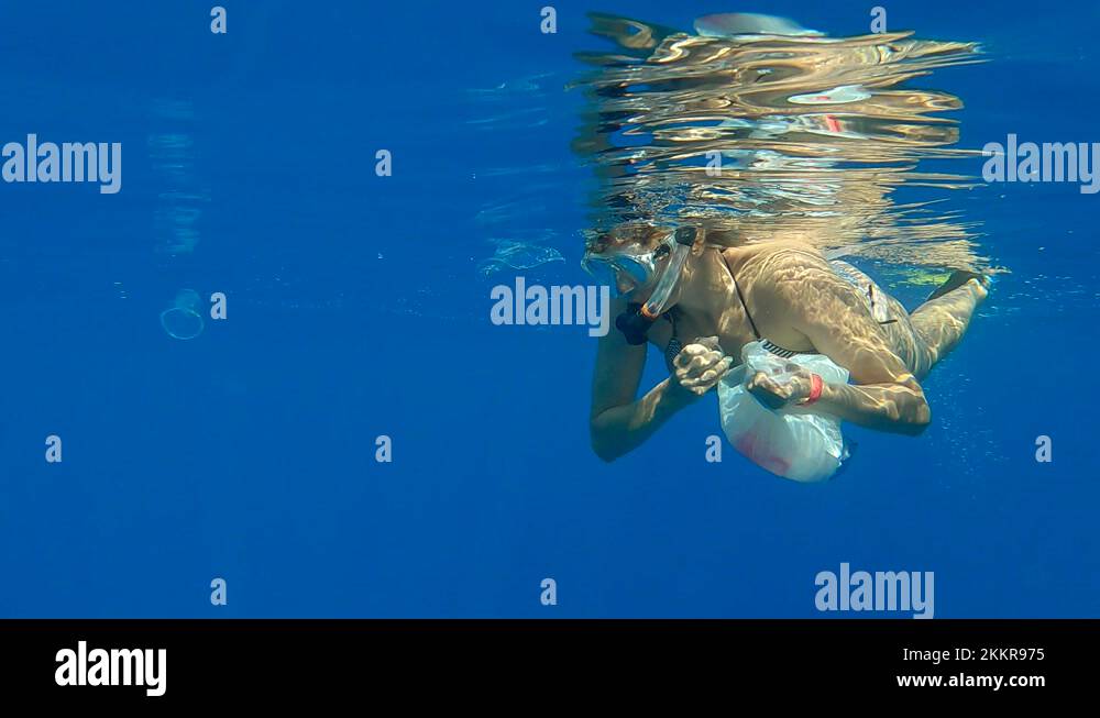 Woman collects plastic trash underwater clean up of a dirty discarded ...
