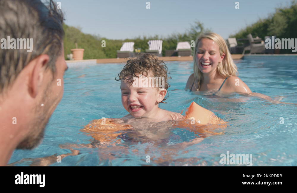 Parents Teaching Son To Swim On Summer Vacation In Outdoor Swimming ...