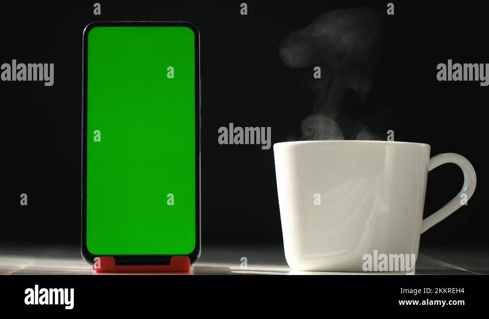 Mobile phone with blank green screen, front view, isolated on black ...