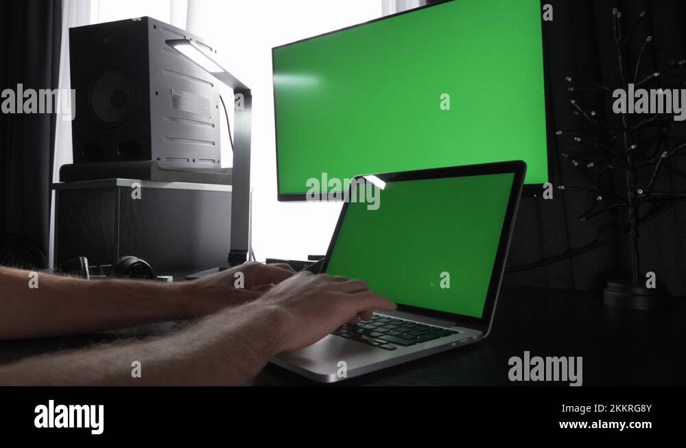 Chroma key green screen. Man is working on laptop computer with green ...