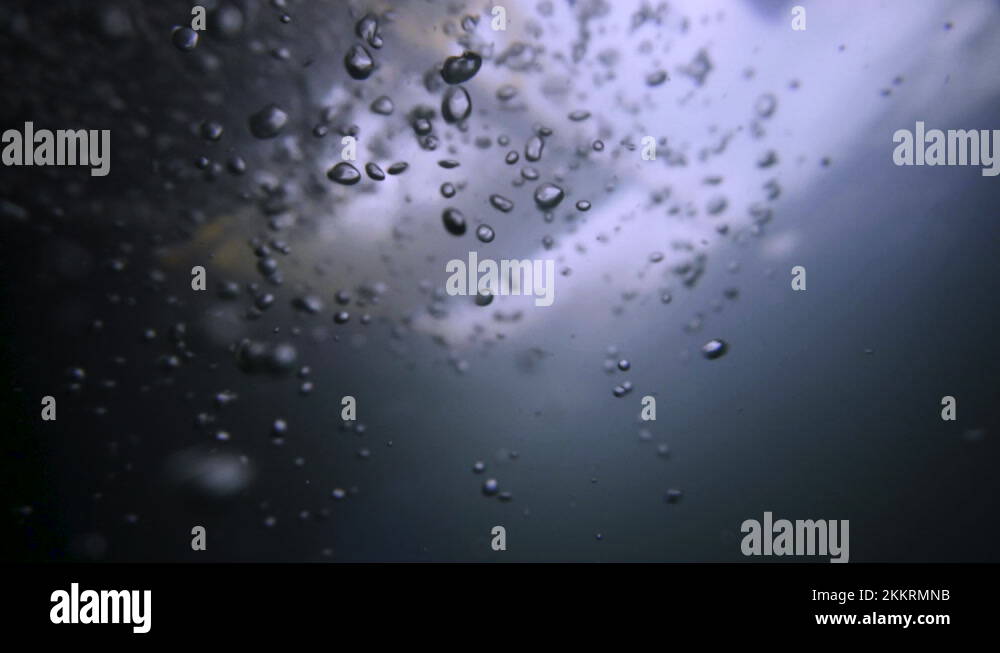 A lot of air bubbles rise to the surface of the water in slow motion ...