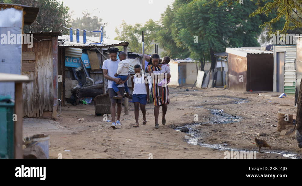 Poverty. Inequality. Poor Black African family walking in a typical ...