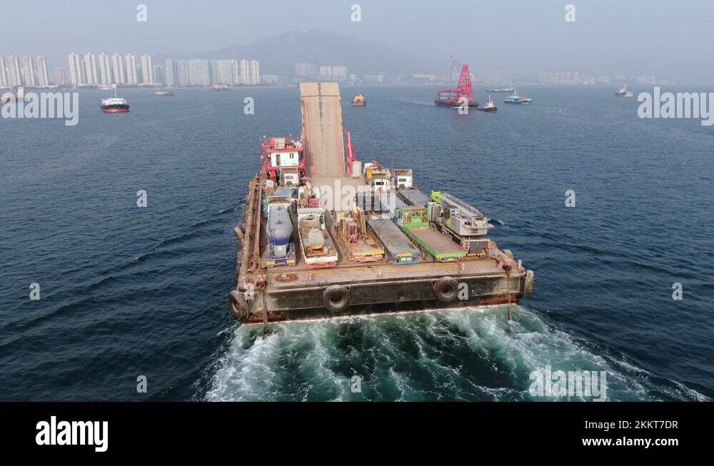 Barge loaded with Concrete mixer trucks pulled to port by a Tugboat in ...