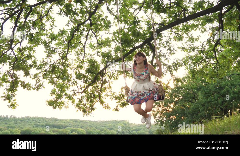 Happy teenage girl swinging high on a swing in the air, rising higher ...