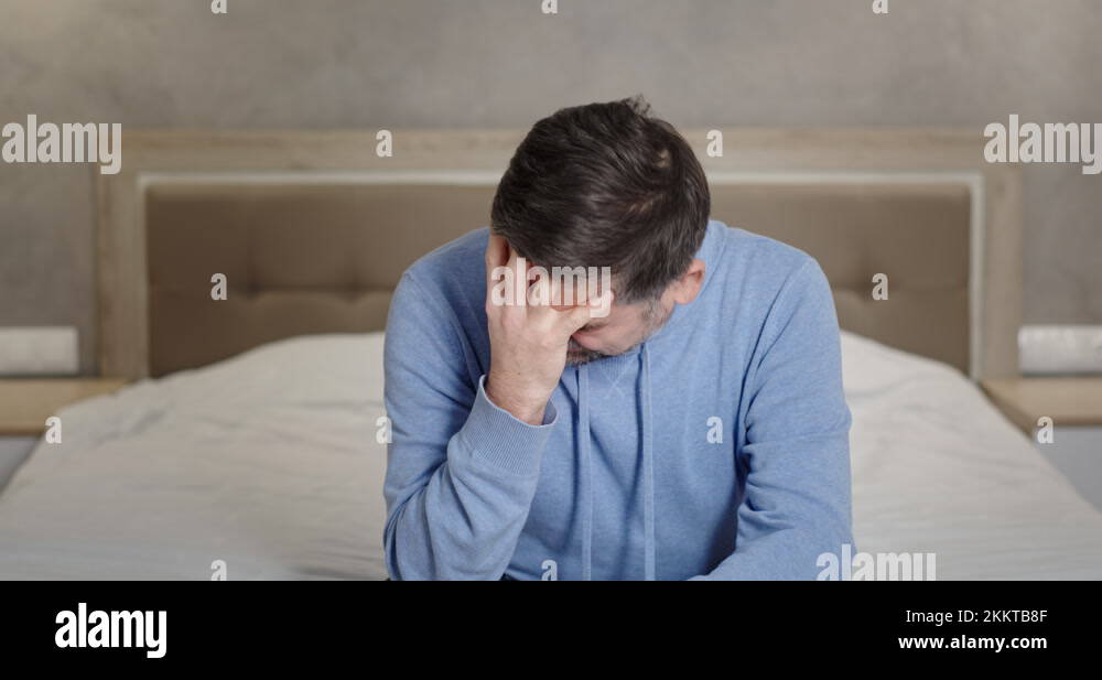 Desperate middle aged man crying on bed. Stressed mature male taking ...