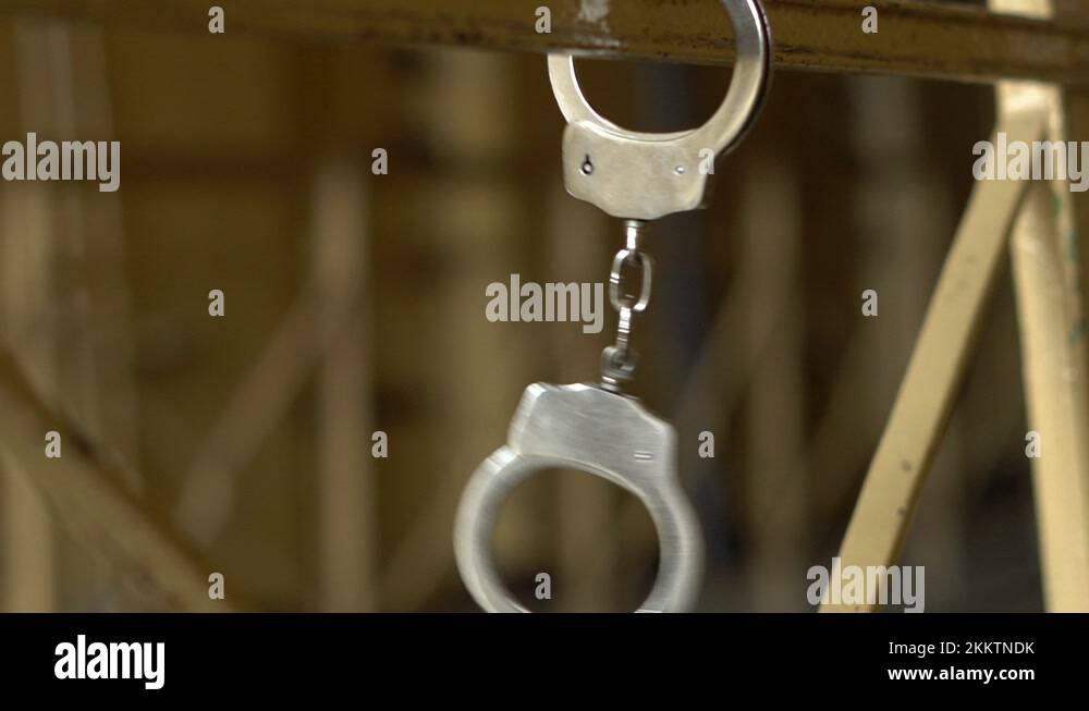 Handcuffs swinging on the handrail on a prison or arrest background ...