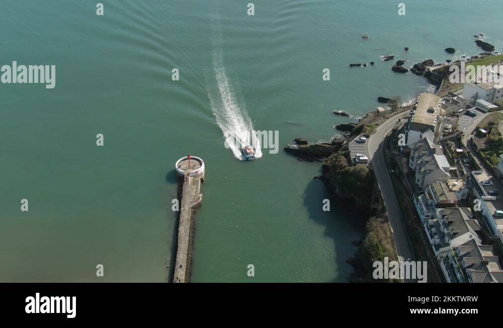 A fishing vessel enters port in Looe town. Aerial top down view of the ...
