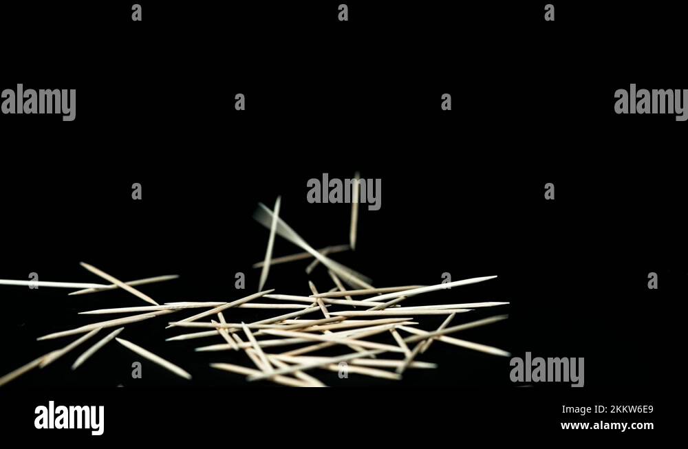 light wooden toothpicks fall in front of black background on dark Stock ...