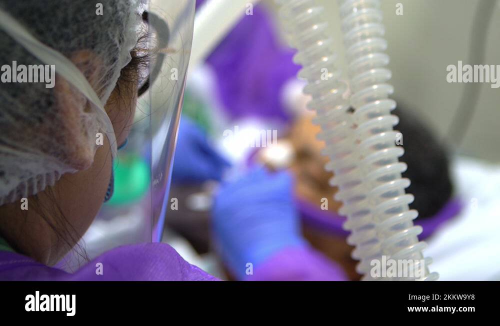 A team of doctors and nurses connect a respirator to a patient with ...