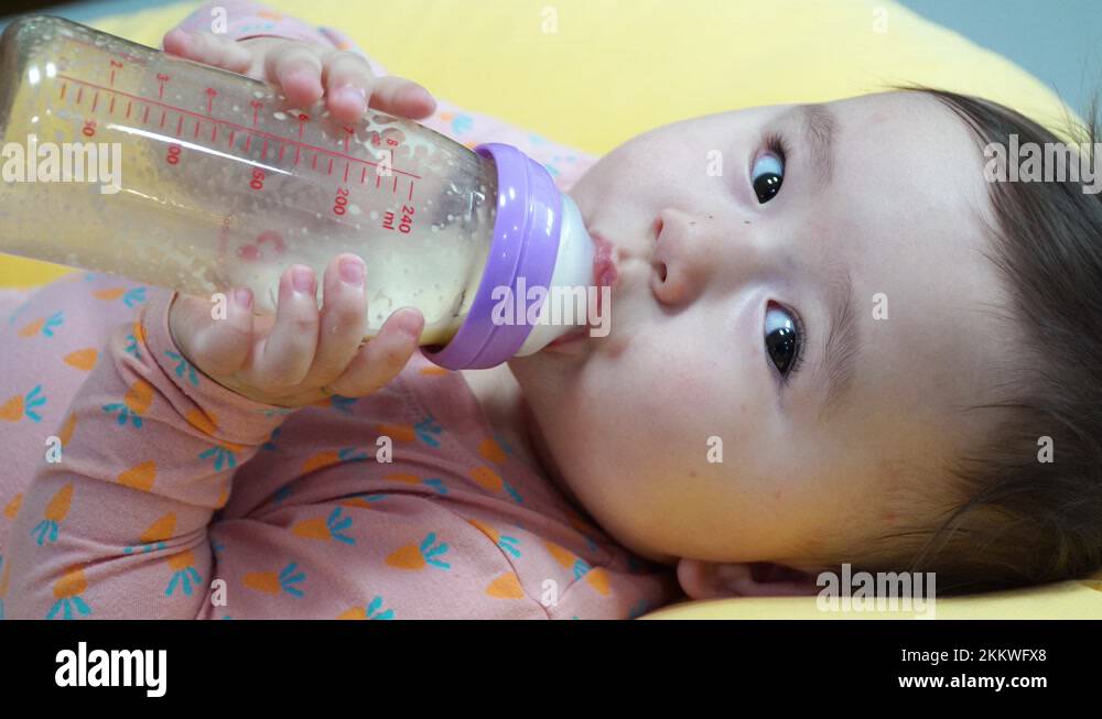 Cute Baby Girl Lying Down And Drinking A Bottle Of Milk - close up ...