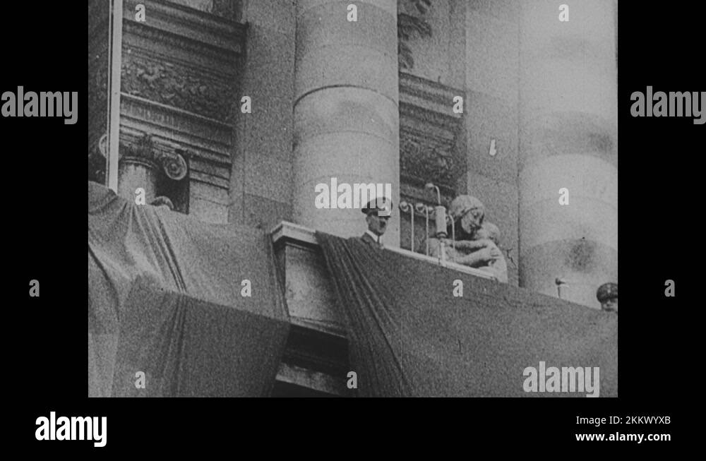 1930s: Adolph Hitler gives speech from balcony of building. Large crowd ...