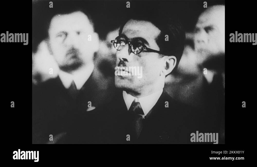 1930s Germany: Huge crowd in hall with swastika symbols. Rudolf Hess in ...