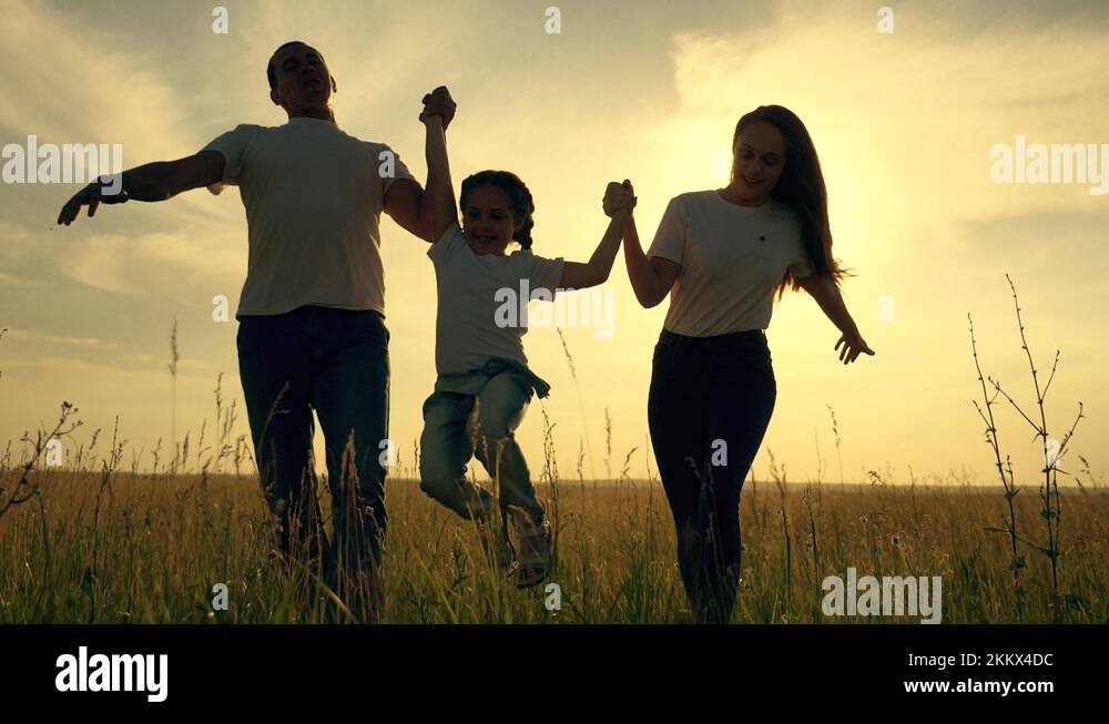 Happy family run in park at sunset. Teamwork. Parents and daughter are ...
