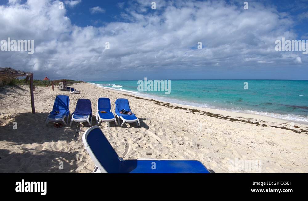Resting benches are placed on the white sand of a paradisiac beach with ...