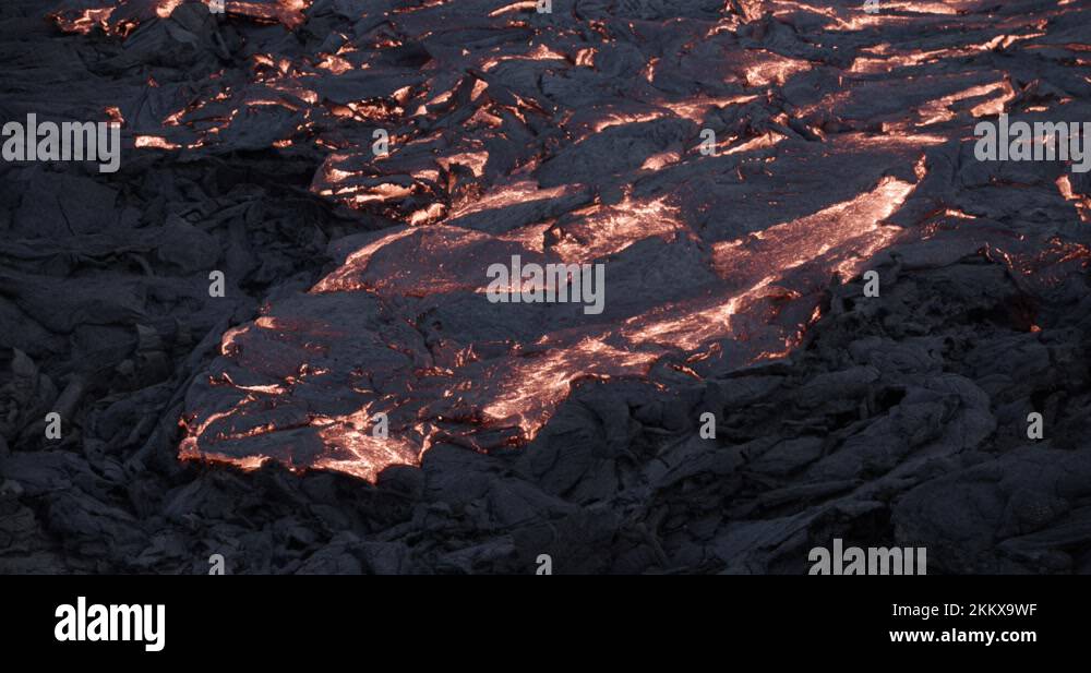 Slow moving hot lava on rough dark basalt surface at volcano eruption ...