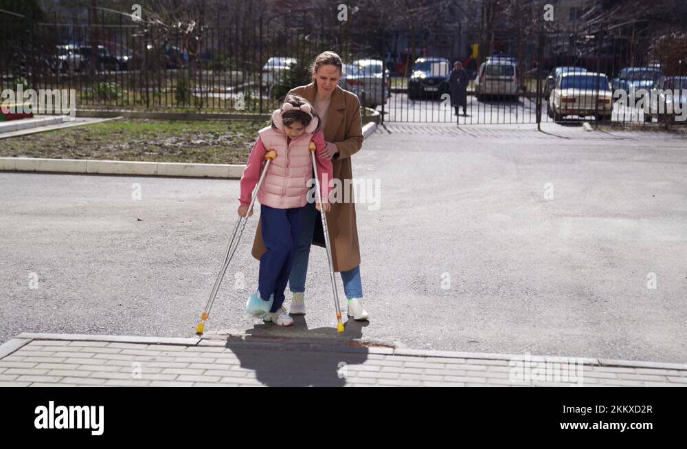 mom helps her daughter learn to walk on crutches. broken ramp and a ...