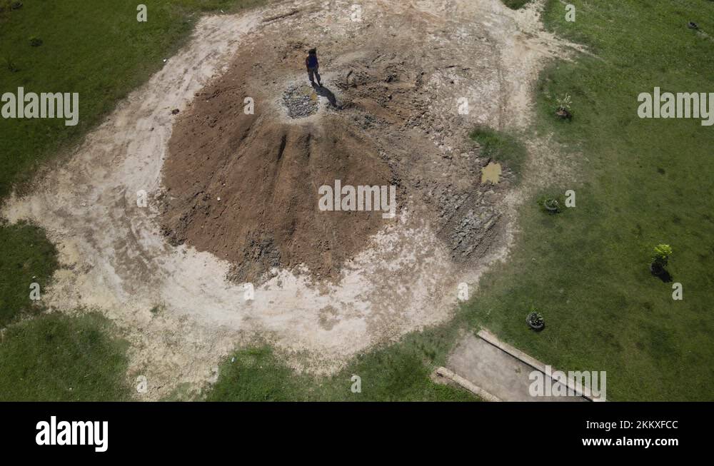 Epic aerial of an East Indian woman standing on a cone shaped mud ...