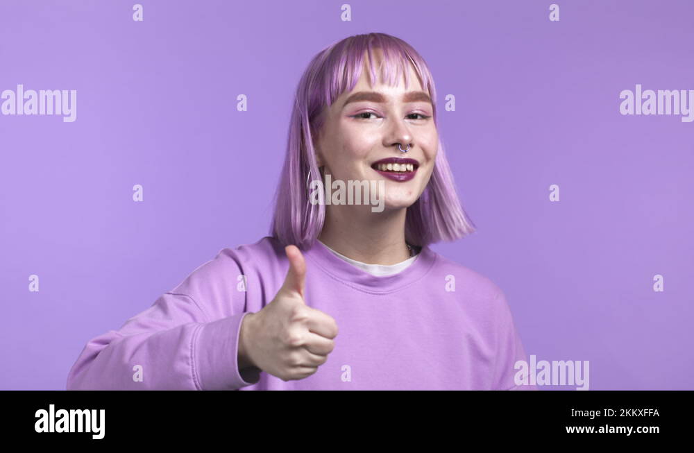 Pretty woman showing thumb up like sign over violet studio background ...