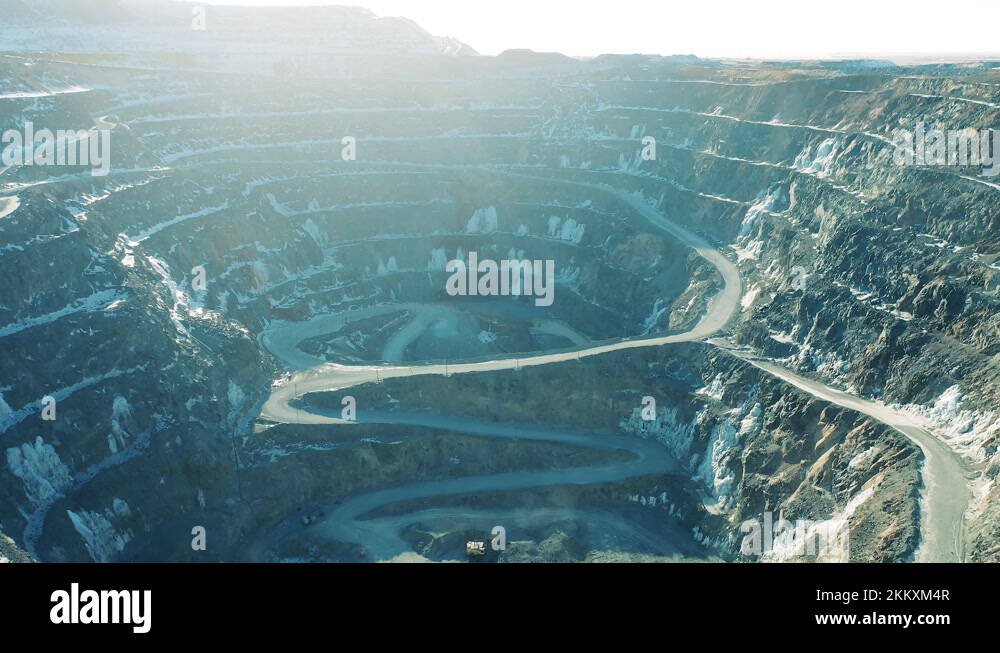 Mine pit with an excavator inside of it in a top view. Open quarry ...